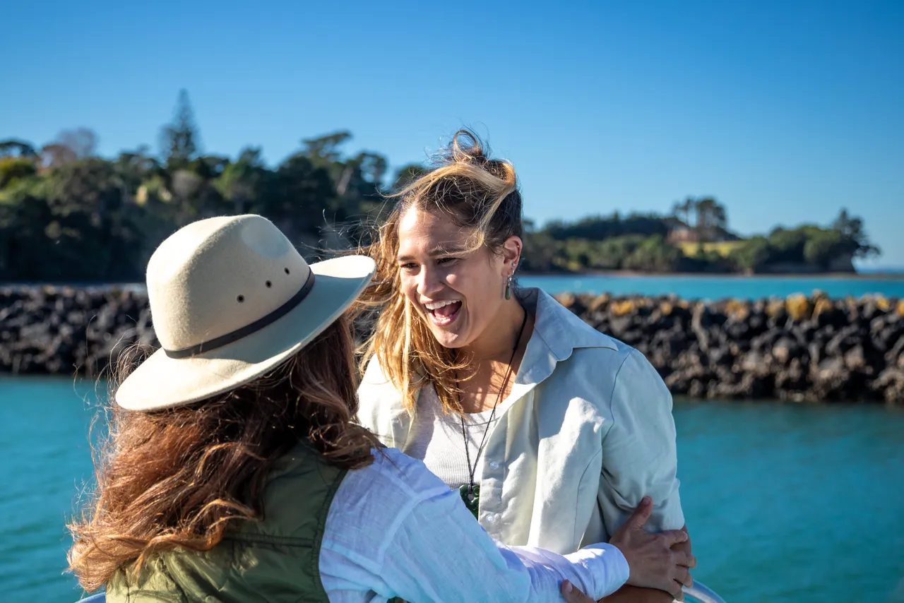 Women embrace with ocean behind them